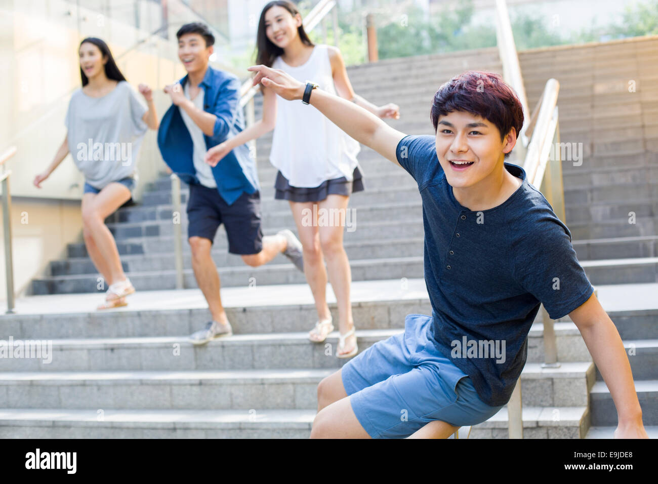 Young man sliding down banister on steps Stock Photo - Alamy