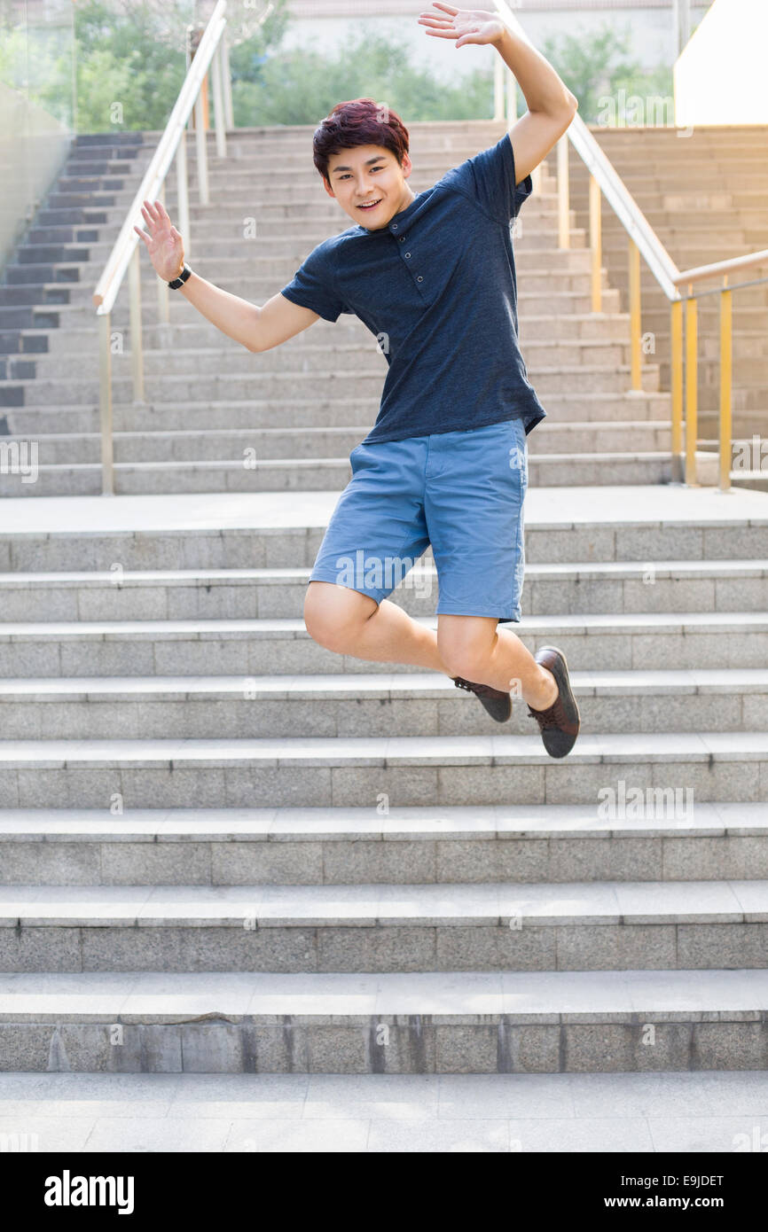 Young man jumping down steps Stock Photo - Alamy