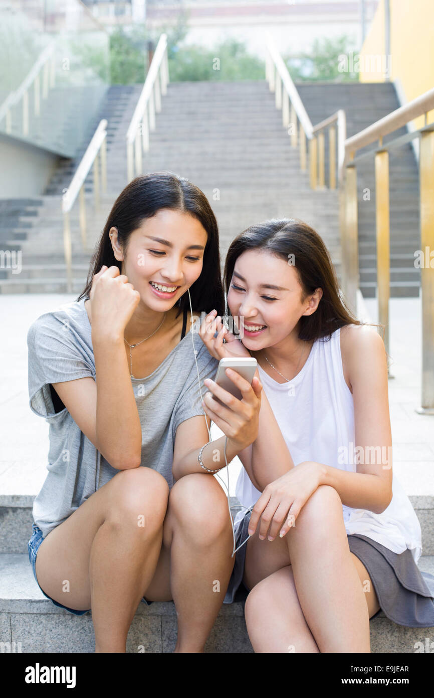 Best female friends listening to earphones Stock Photo - Alamy