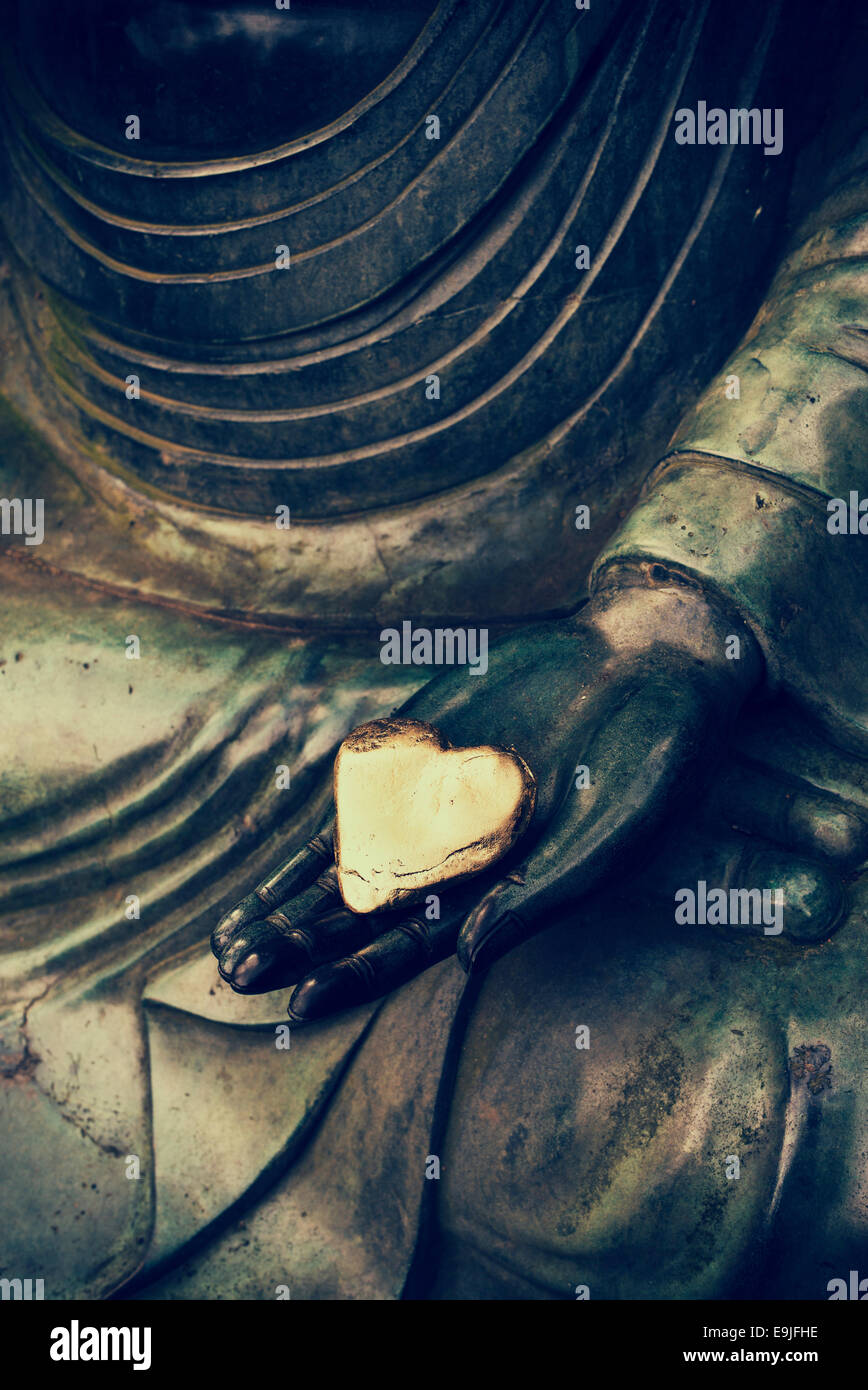 Heart shape gilded pebble on the hand of a very large buddha statue ...