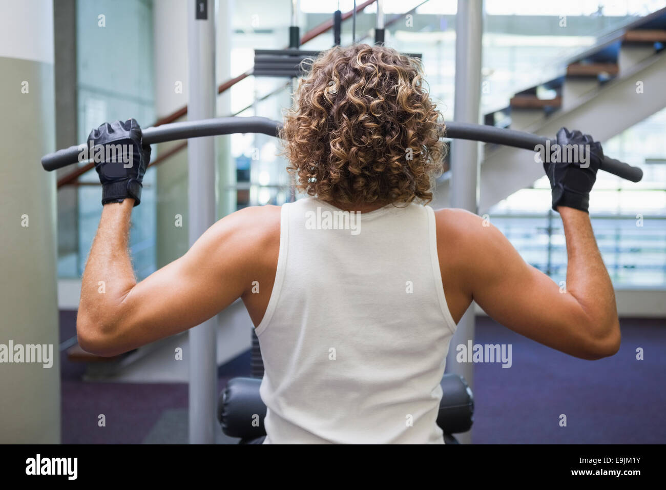 Rear view of a man exercising on a lat machine Stock Photo - Alamy