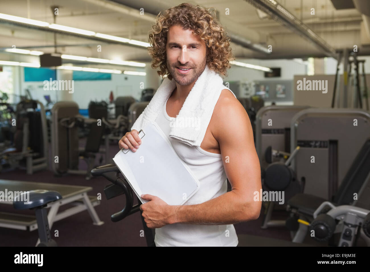 Smiling handsome trainer with clipboard in gym Stock Photo - Alamy