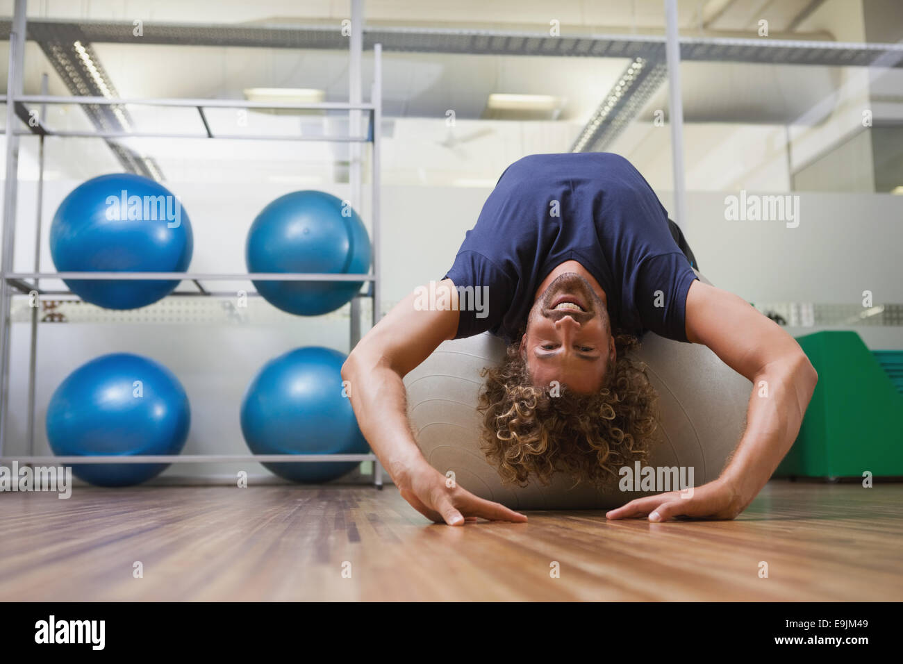 Handsome man stretching on fitness ball in gym Stock Photo - Alamy