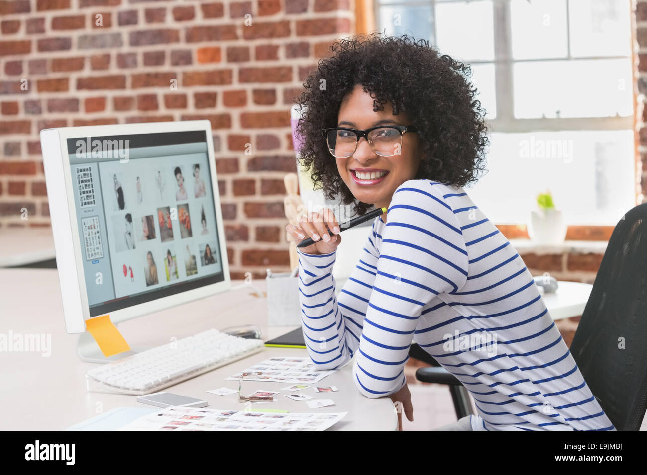 Smiling female photo editor at office desk Stock Photo - Alamy