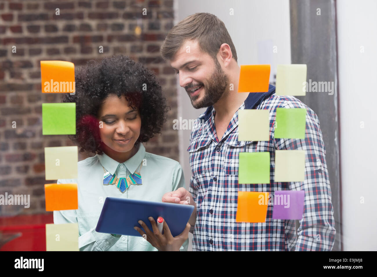 Team using digital tablet by sticky notes on window Stock Photo - Alamy