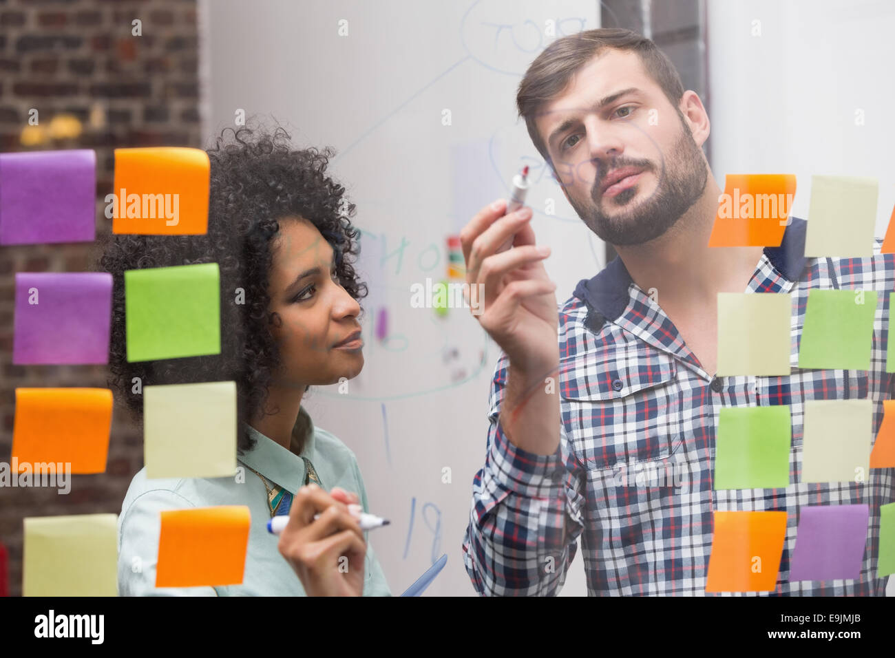 Team looking at sticky notes on window Stock Photo - Alamy