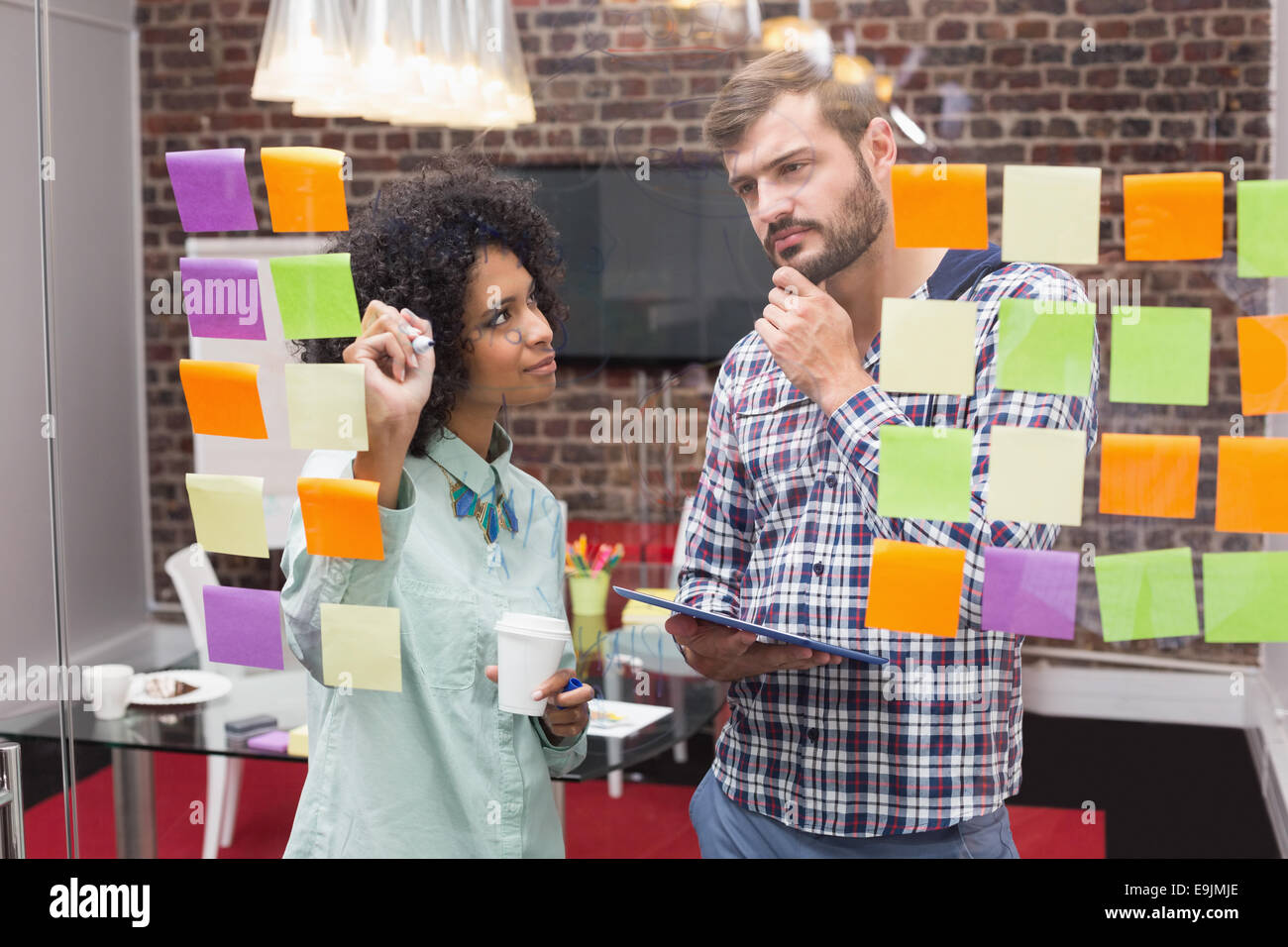 Team looking at sticky notes on window Stock Photo - Alamy