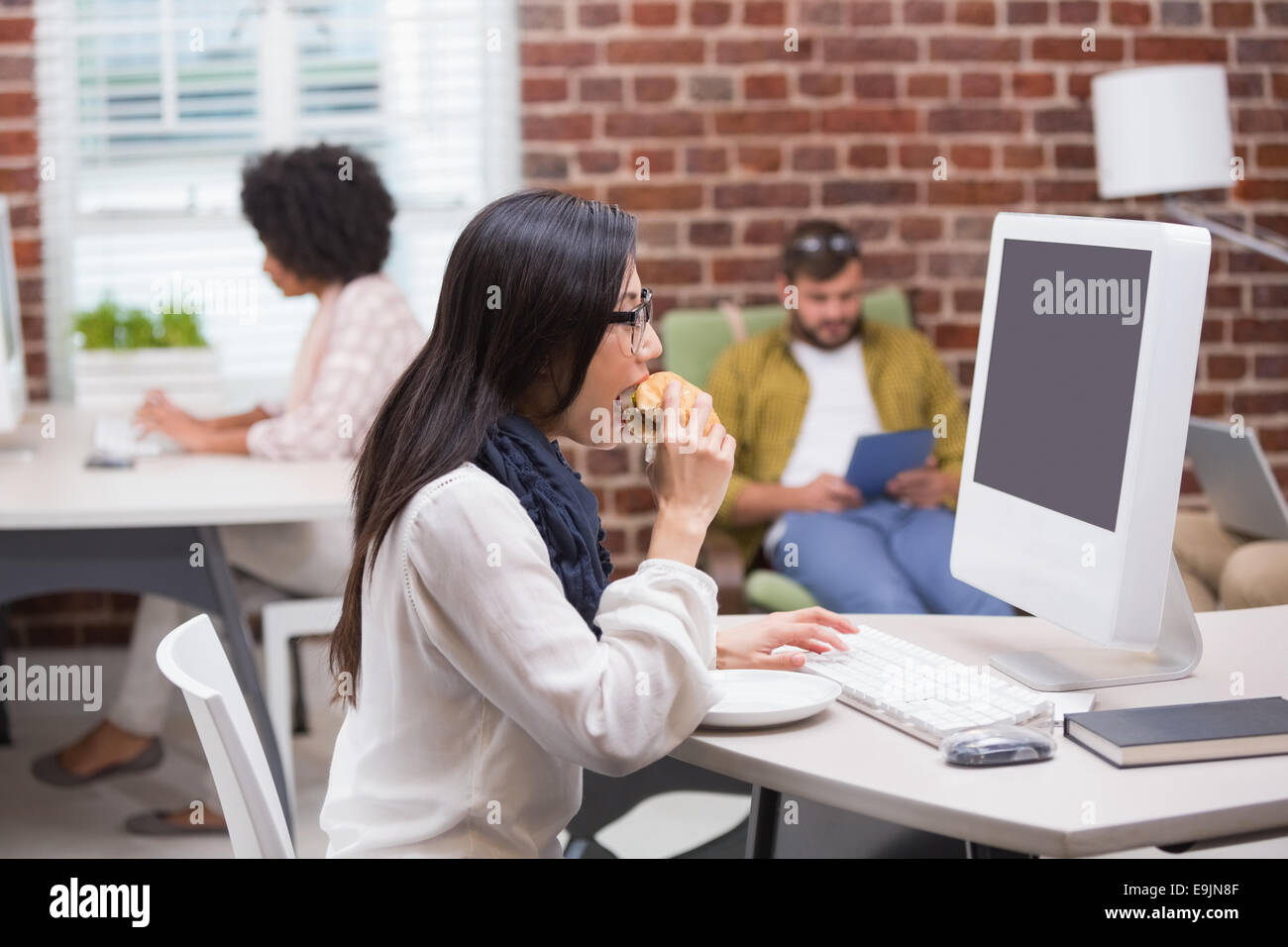 Casual woman drinking coffee while using computer Stock Photo - Alamy