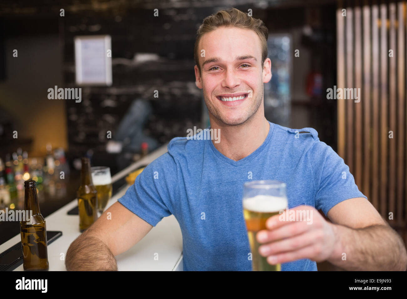 Young man holding pint of beer Stock Photo - Alamy