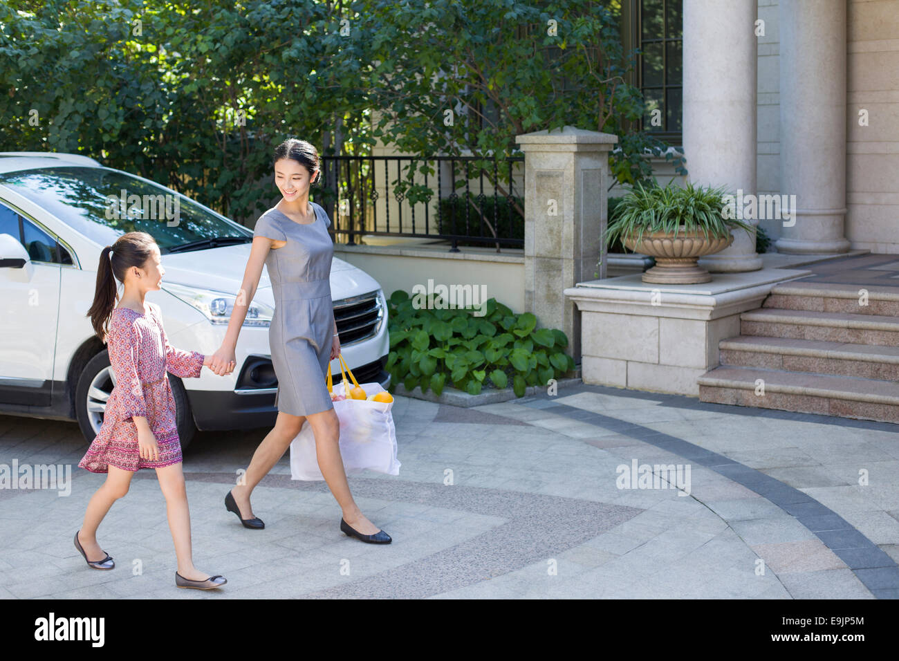 Mother and daughter walking towards home Stock Photo - Alamy