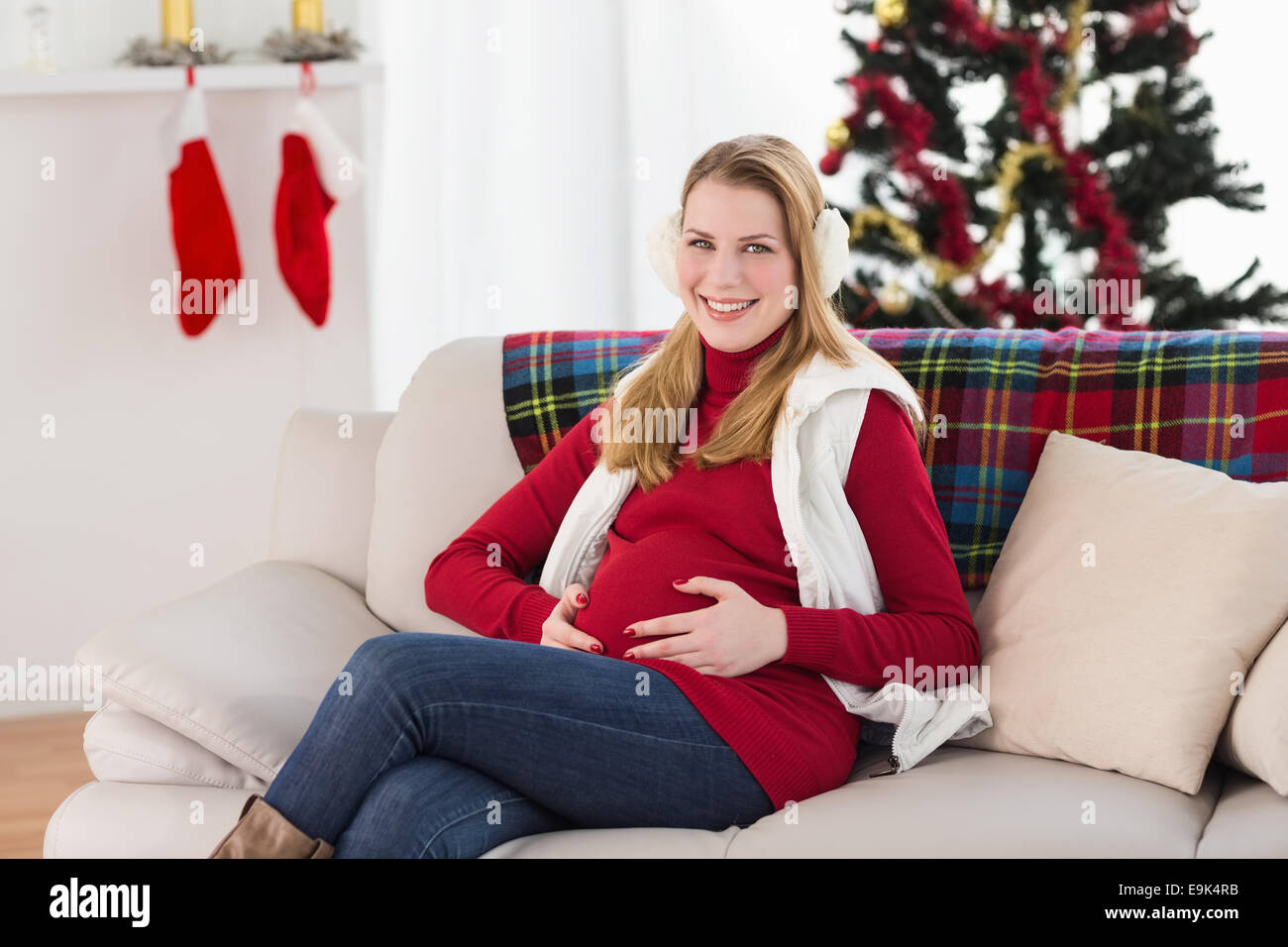 Beautiful pregnant woman holding her belly sitting on couch Stock Photo ...