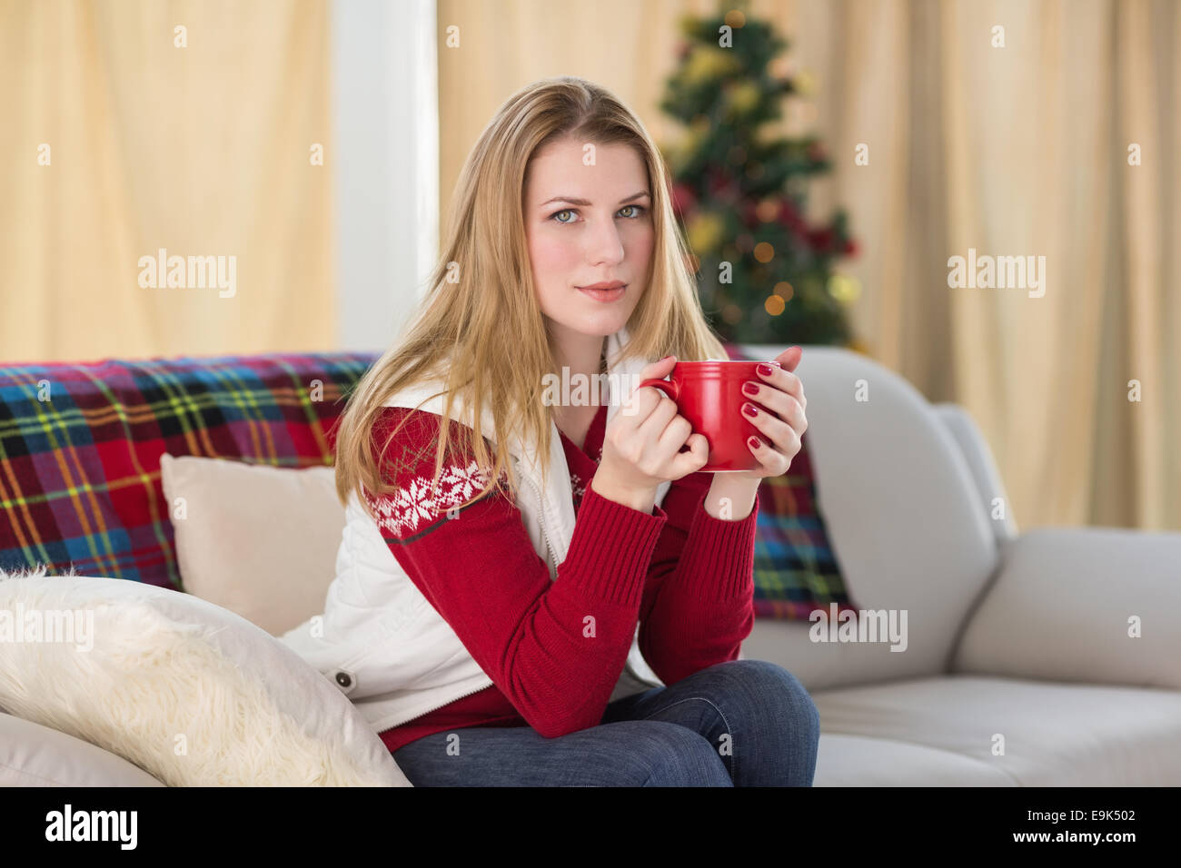 Cheerful cute blonde sitting on couch holding mug Stock Photo - Alamy