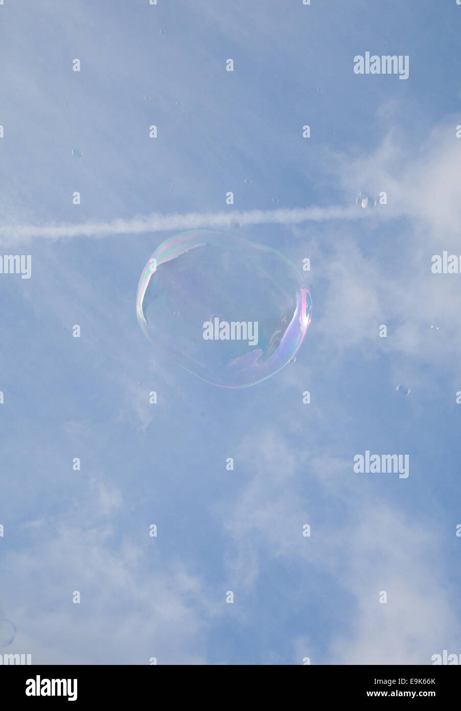 Giant bubble floating off into a blue cloudy sky with other smaller ...