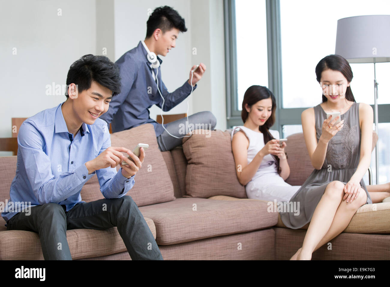 Young friends sitting on the sofa with smart phones Stock Photo - Alamy