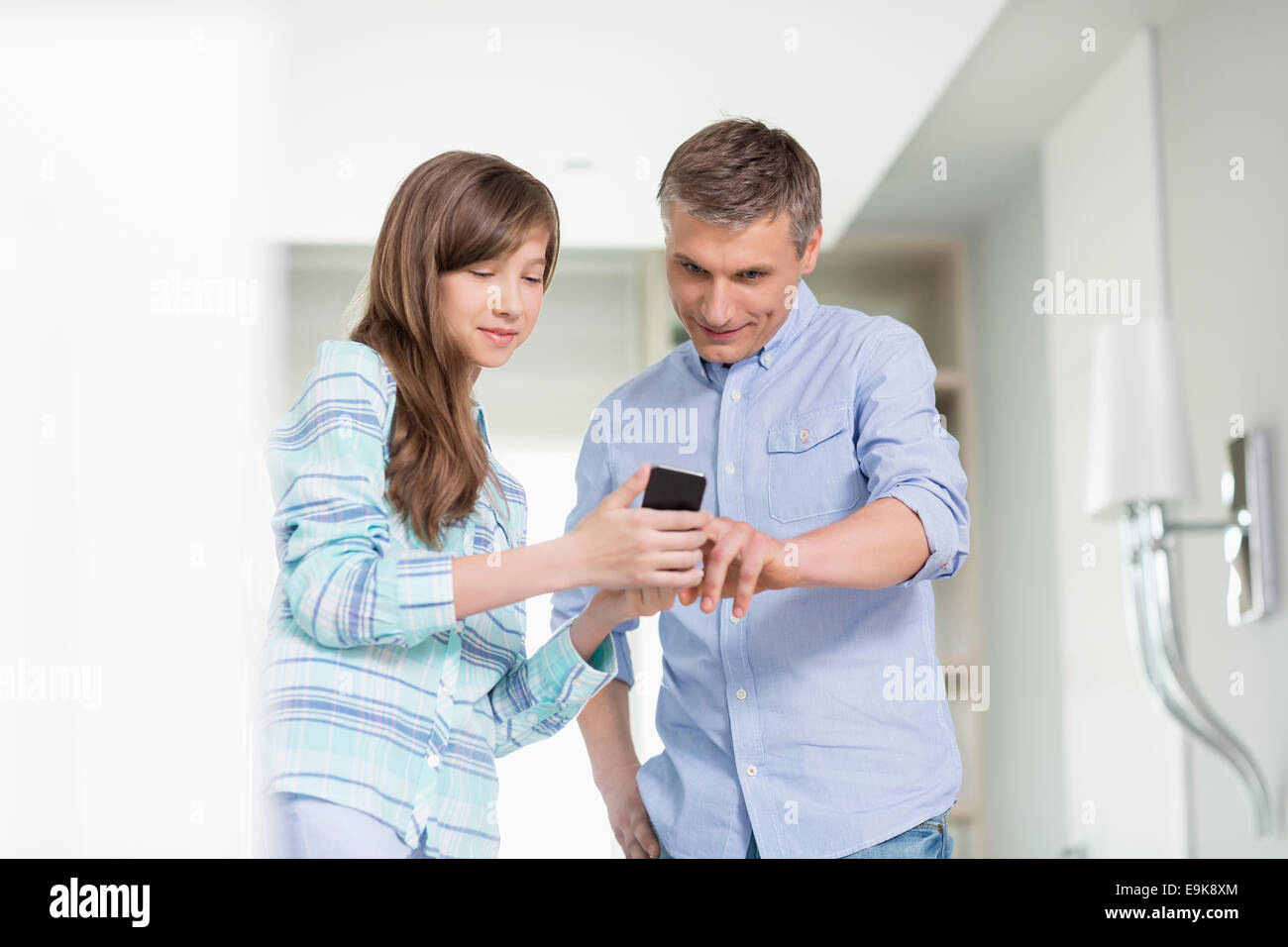 Father and daughter using smart phone at home Stock Photo - Alamy