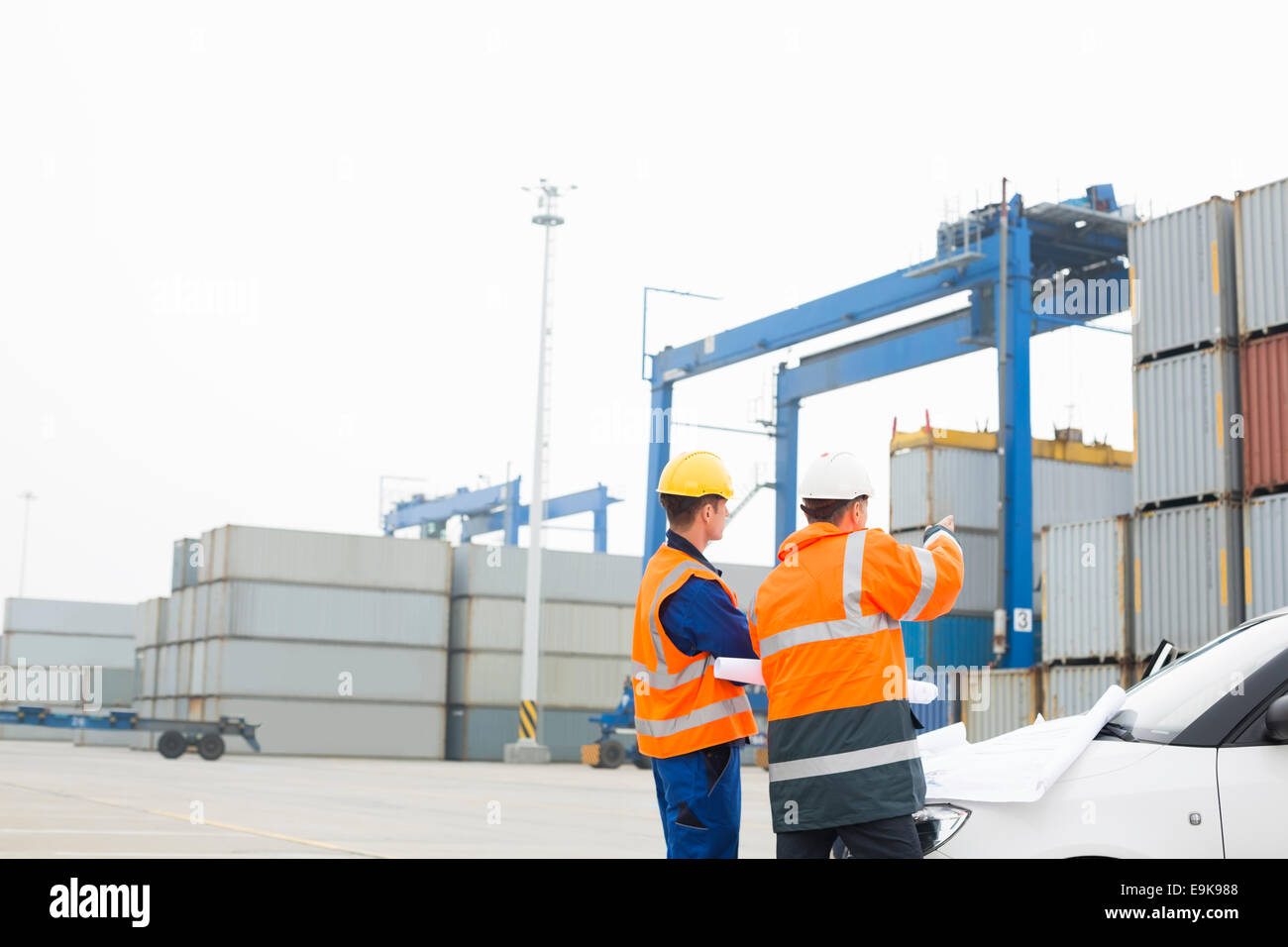 Workers discussing over blueprint in shipping yard Stock Photo - Alamy