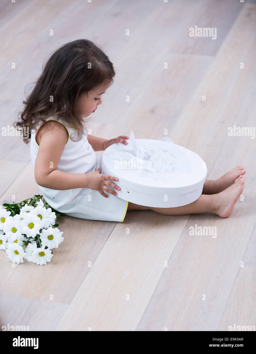 Full length side of little girl opening gift box on floor at home Stock ...