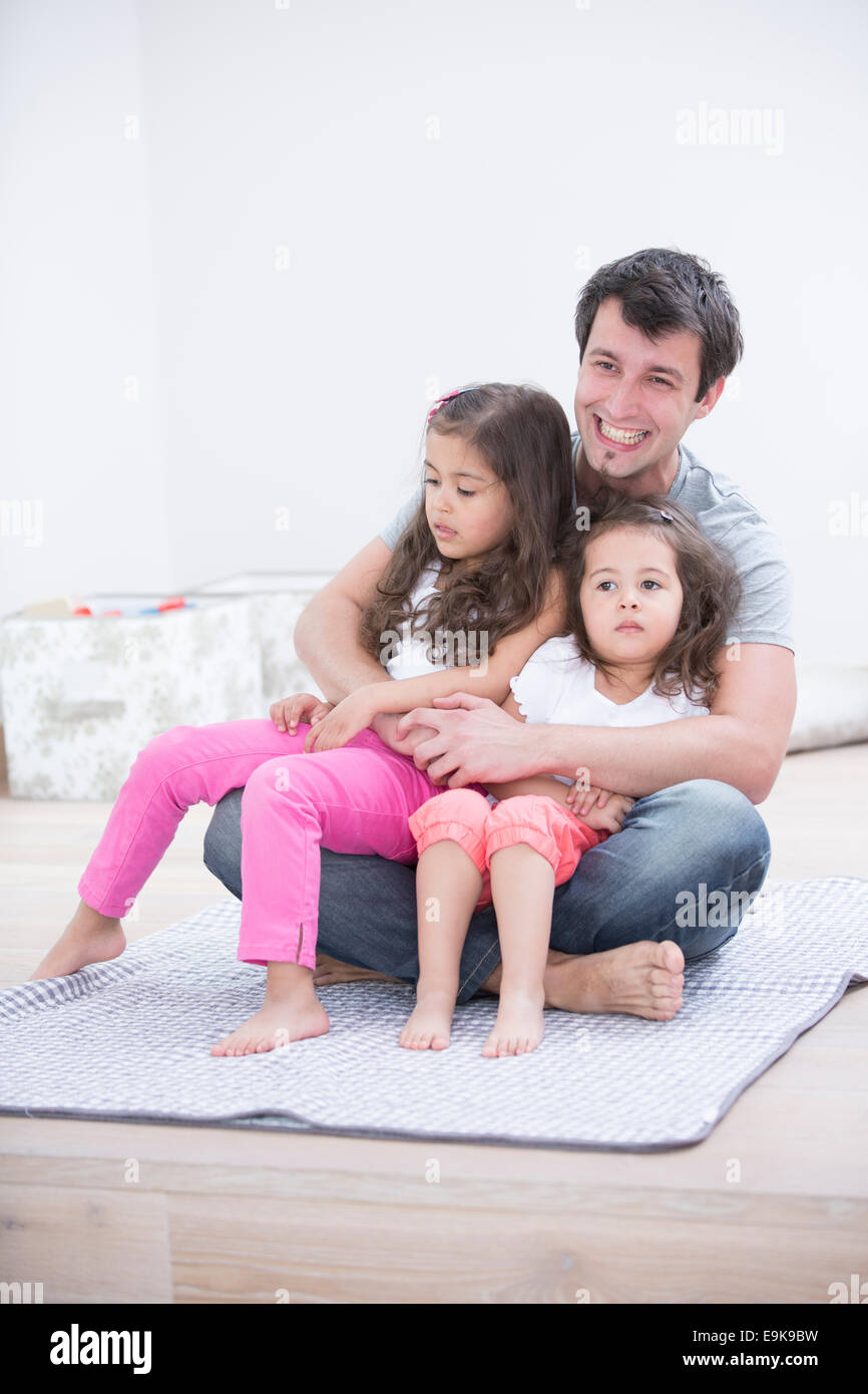 Smiling young man with daughters sitting in his lap at home Stock Photo ...