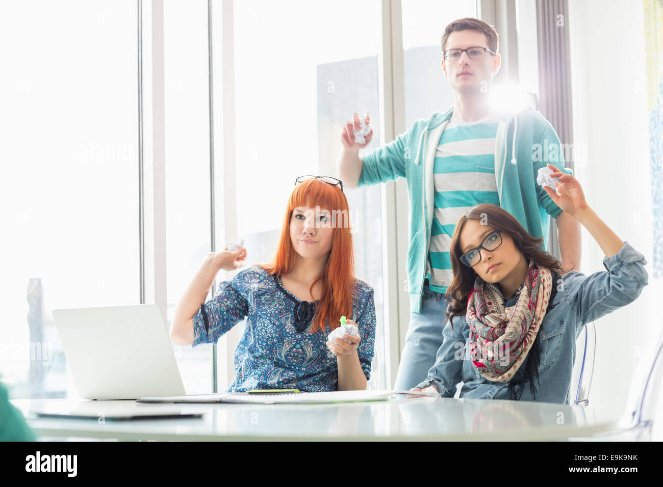 Angry businesspeople throwing paper balls in creative office Stock ...