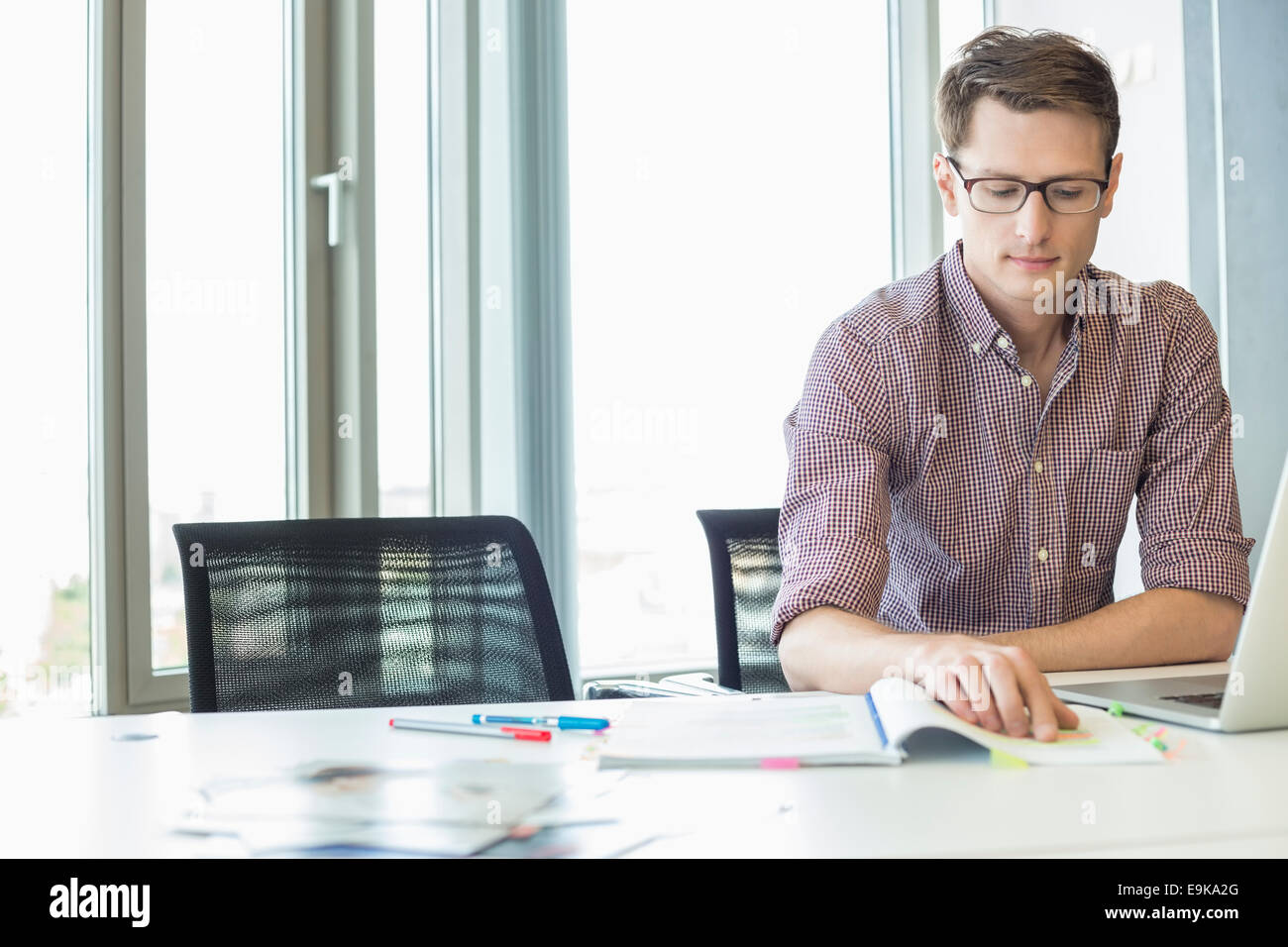 Creative businessman reading file at desk in office Stock Photo - Alamy