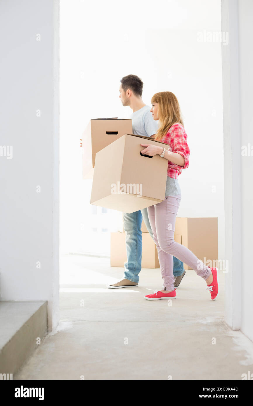 Full-length side view of couple walking with cardboard boxes Stock ...