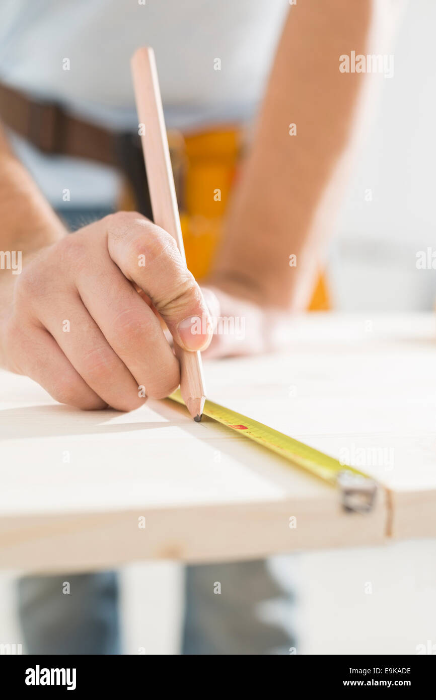 Midsection of carpenter marking table with measure tape Stock Photo - Alamy