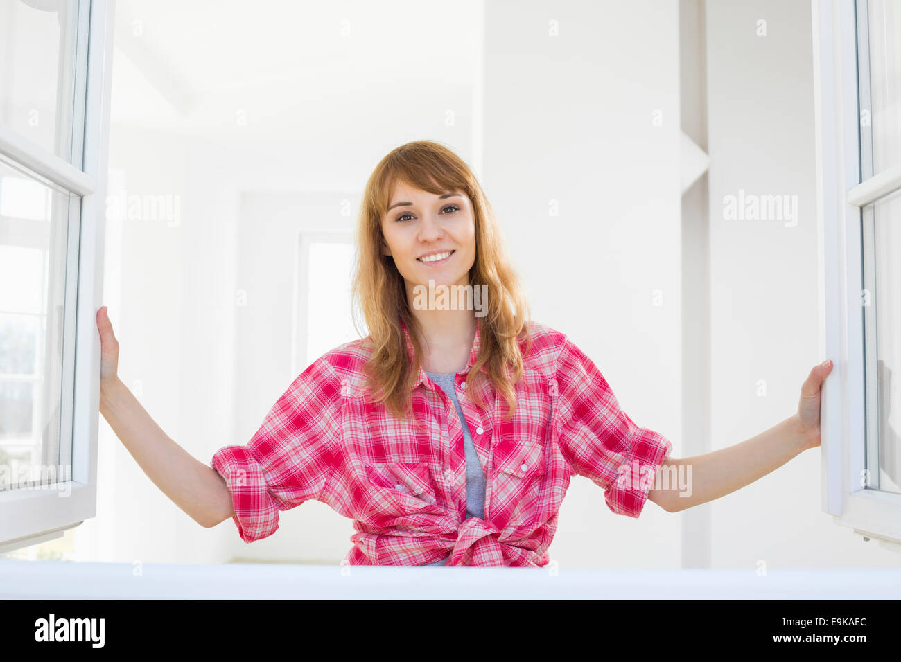 Smiling woman looking through window Stock Photo - Alamy
