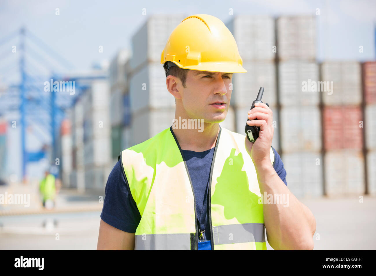 Mid adult man using walkie-talkie in shipping yard Stock Photo - Alamy