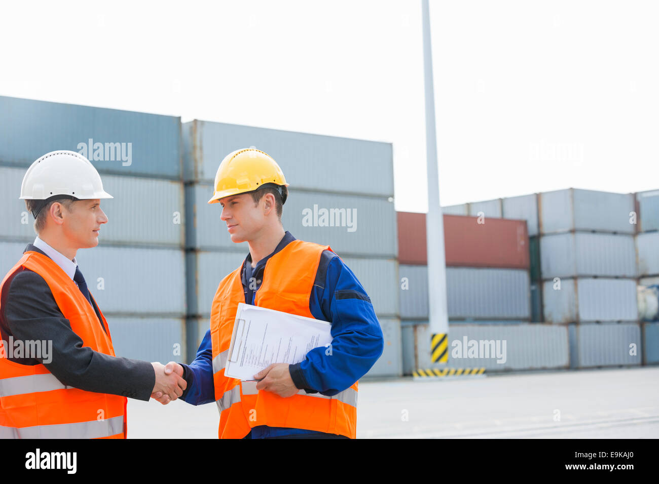 Workers shaking hands in shipping yard Stock Photo - Alamy