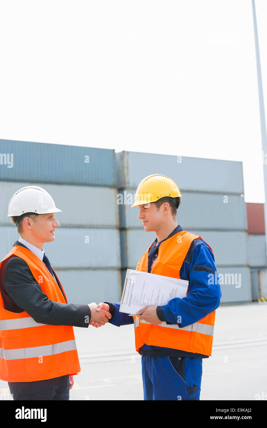 Side view of workers shaking hands in shipping yard Stock Photo - Alamy