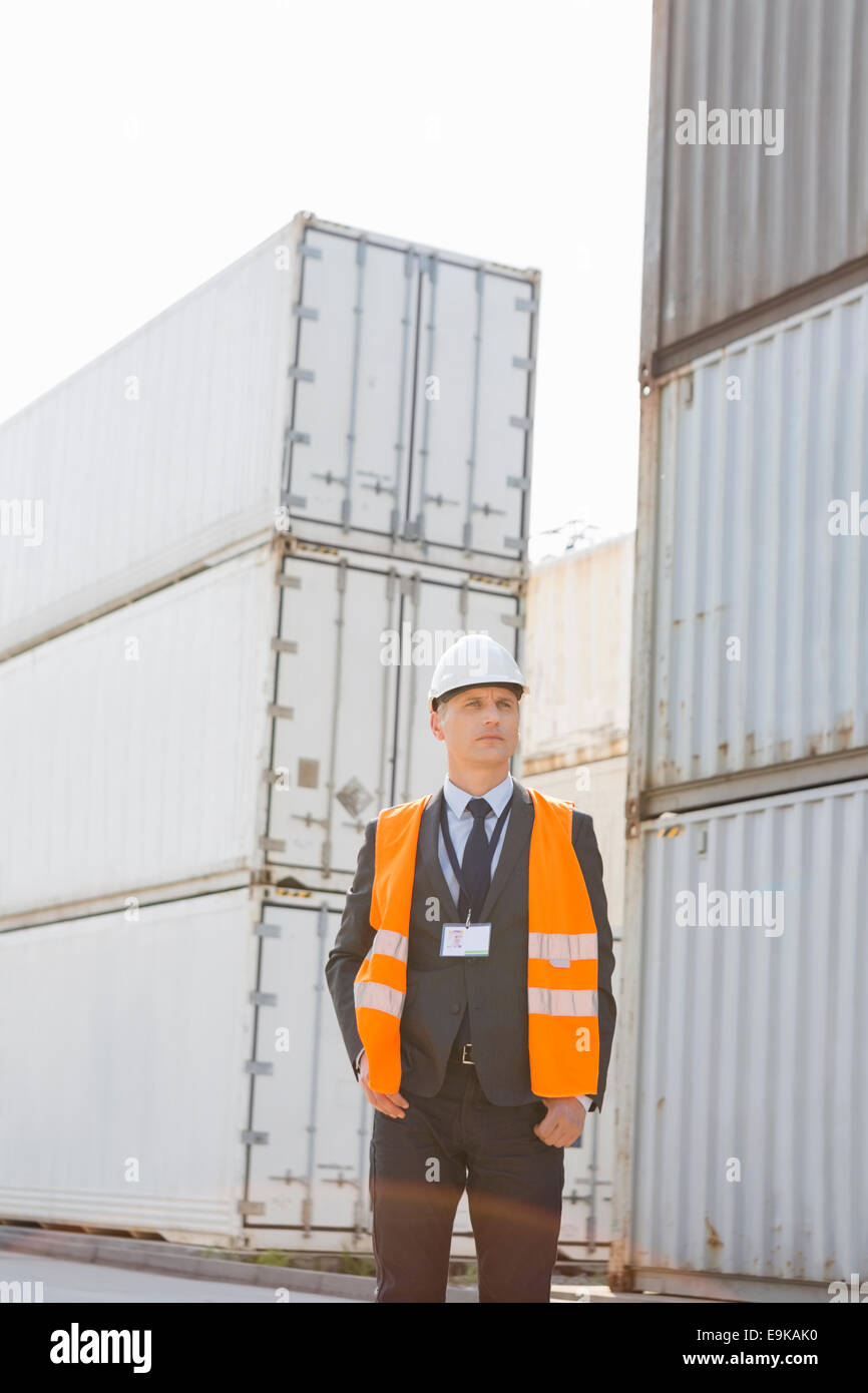 Middle-aged man standing against cargo containers in shipping yard ...