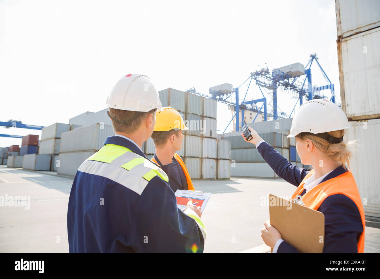 Female supervisor discussing with workers in shipping yard Stock Photo ...