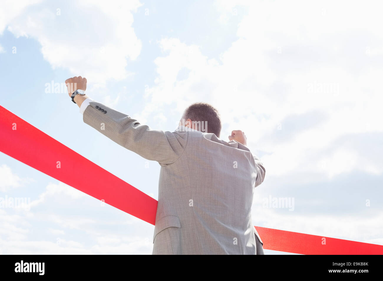 Rear view of businessman crossing finish line against sky Stock Photo ...