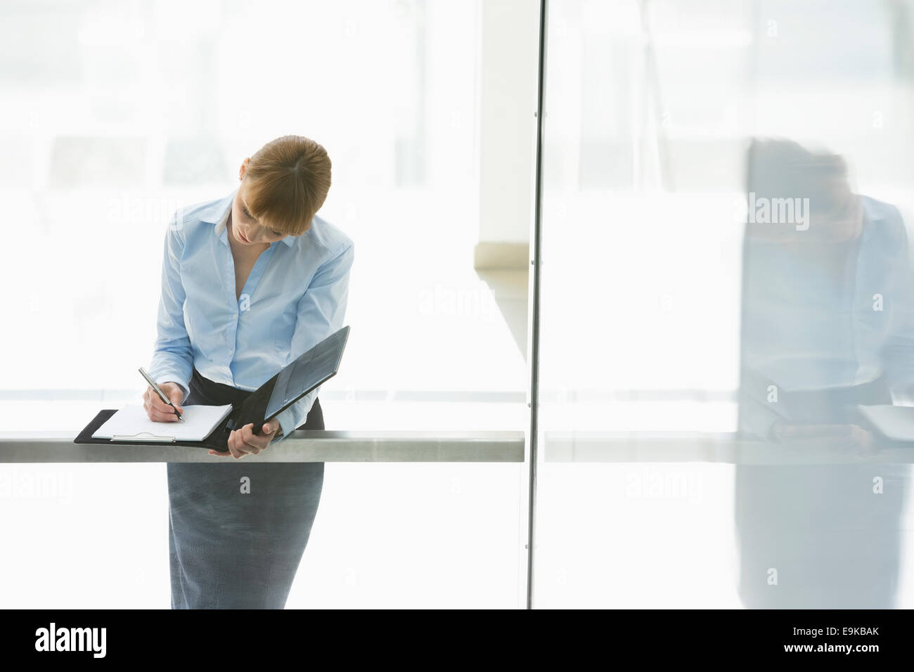 Businesswoman writing on document in office Stock Photo - Alamy