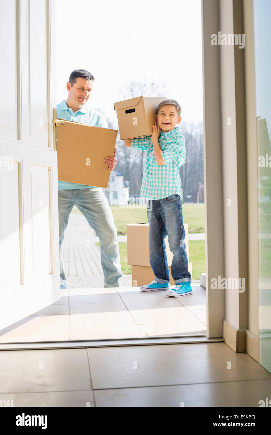 Happy father and son with cardboard boxes entering into new house Stock ...