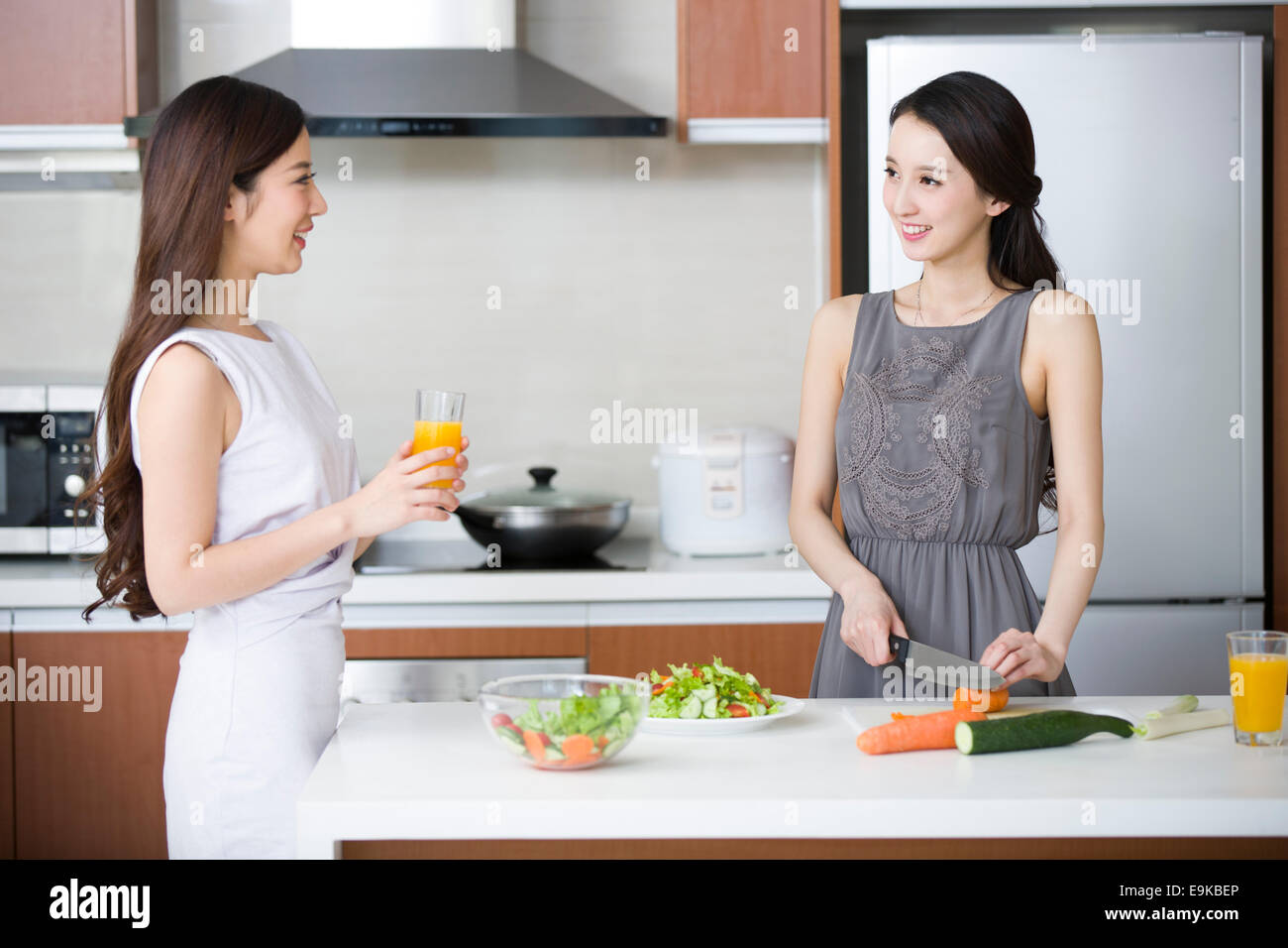 Young woman cooking and talking with her friend in the kitchen Stock ...