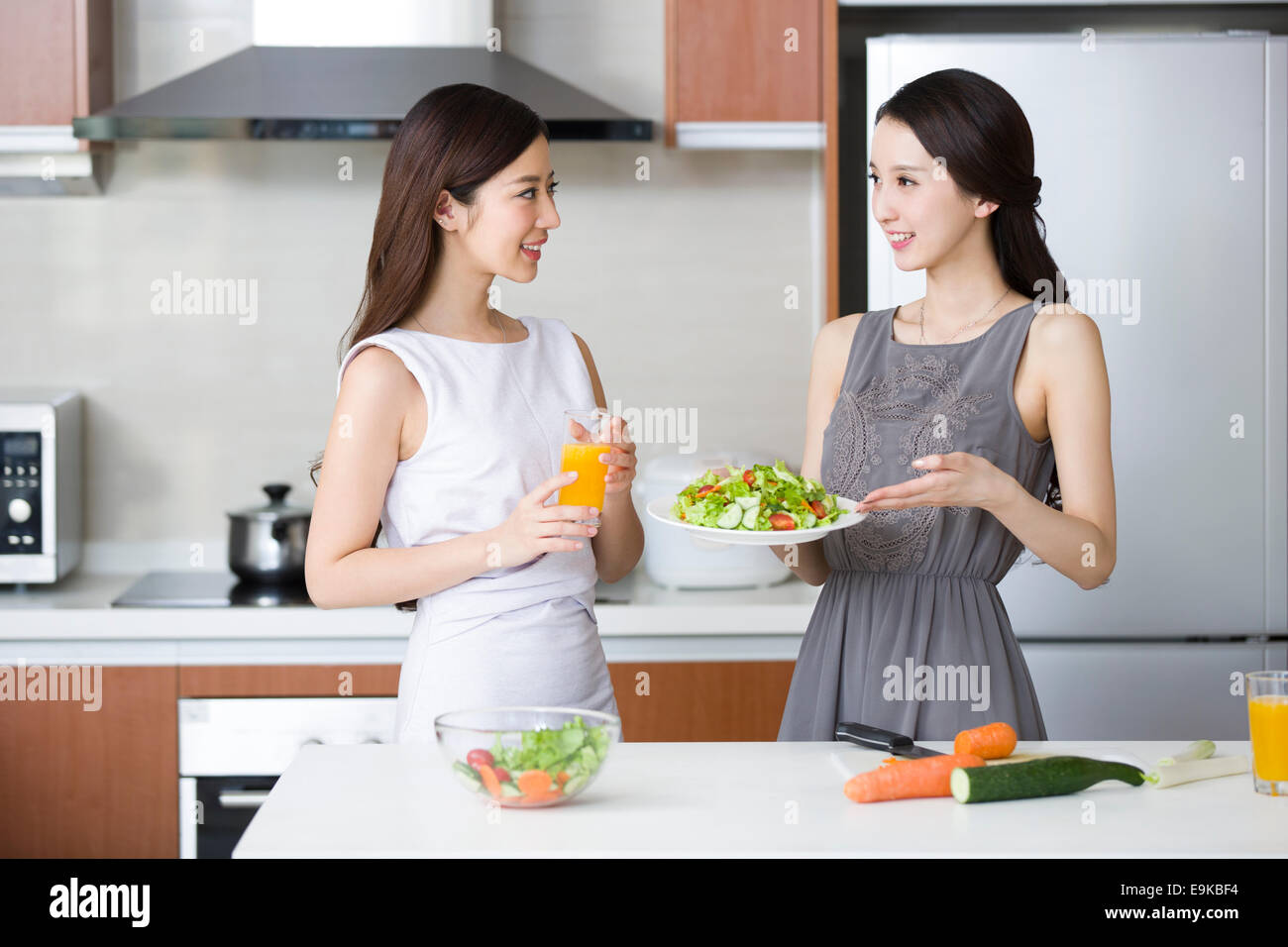 Young woman cooking and talking with her friend in the kitchen Stock ...