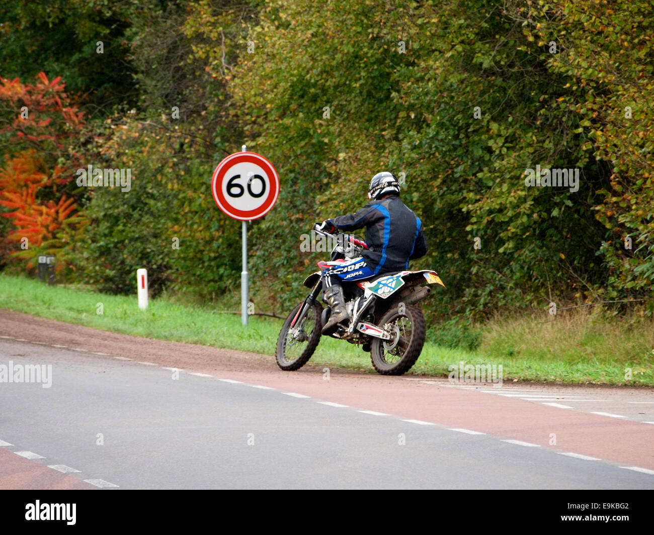 Man on Husqvarna offroad motorcycle passing 60 kmh speed limit sign in ...