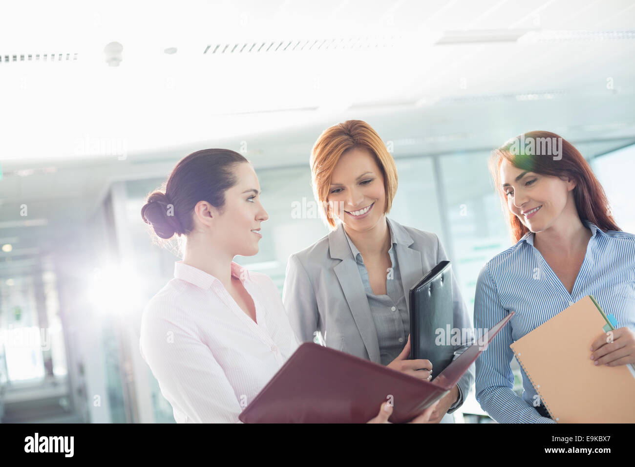 Businesswomen with file folders discussing in office Stock Photo - Alamy
