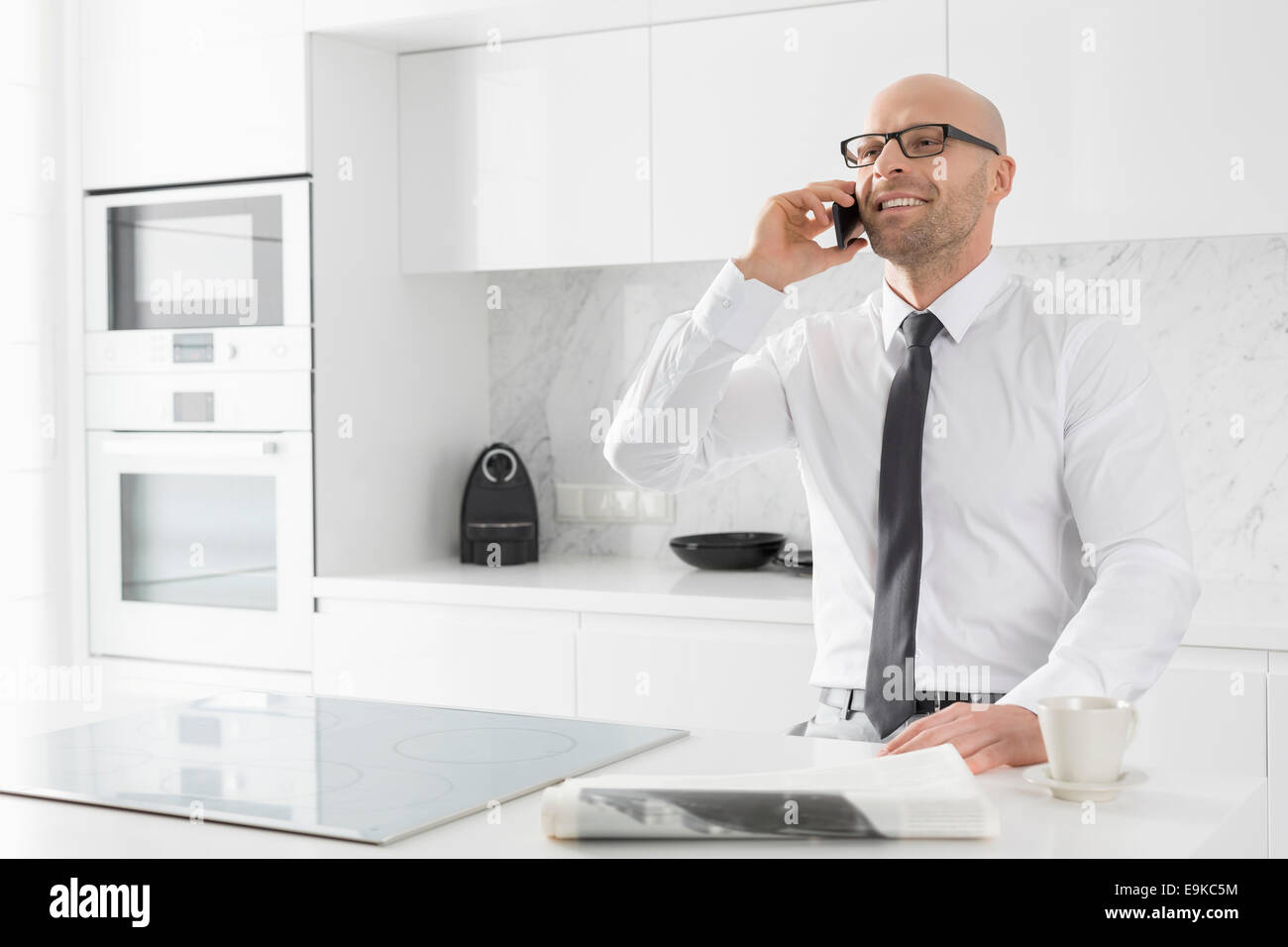 Mid adult businessman on call at kitchen counter Stock Photo - Alamy
