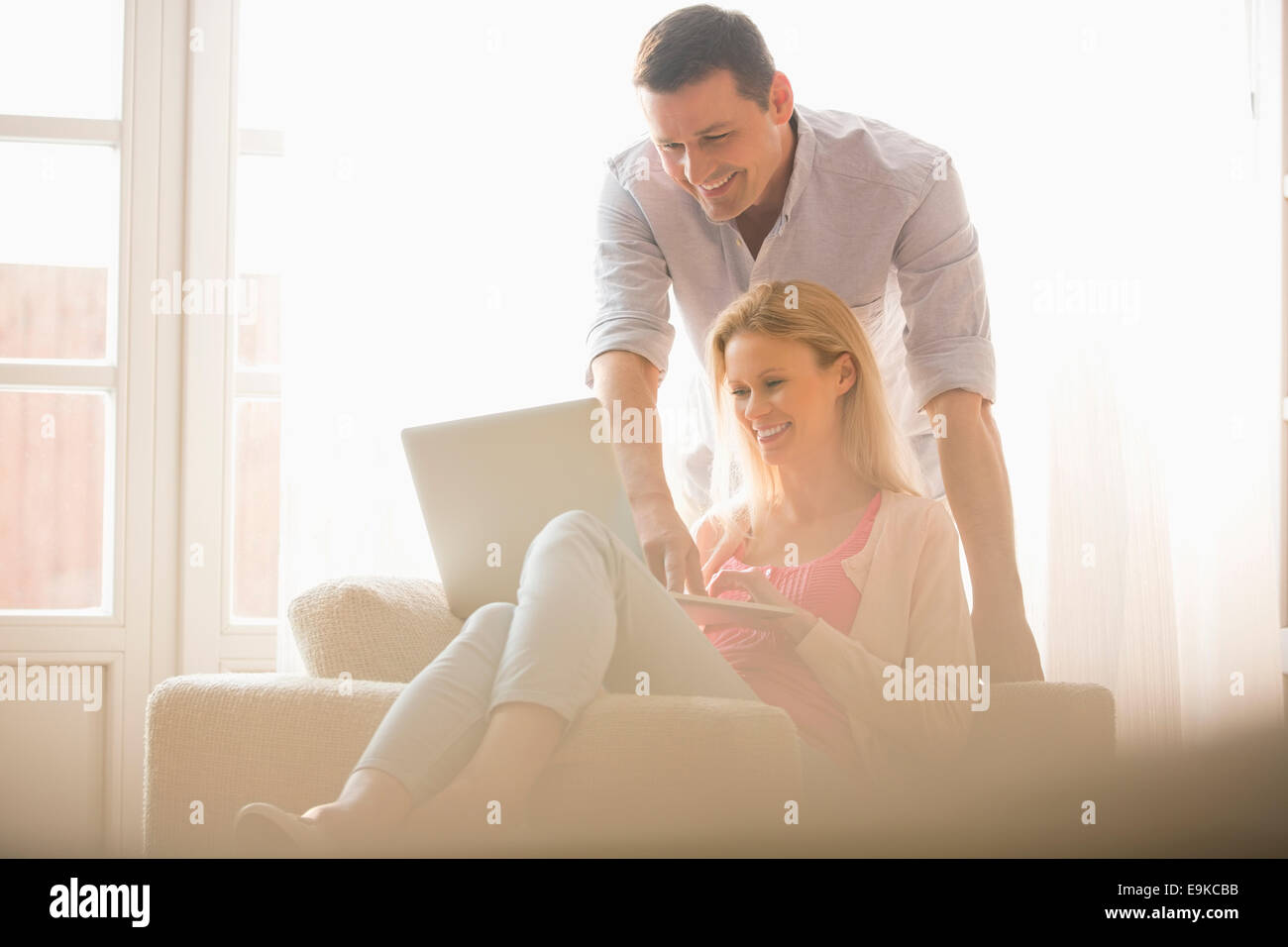 Happy couple using laptop together at home Stock Photo - Alamy