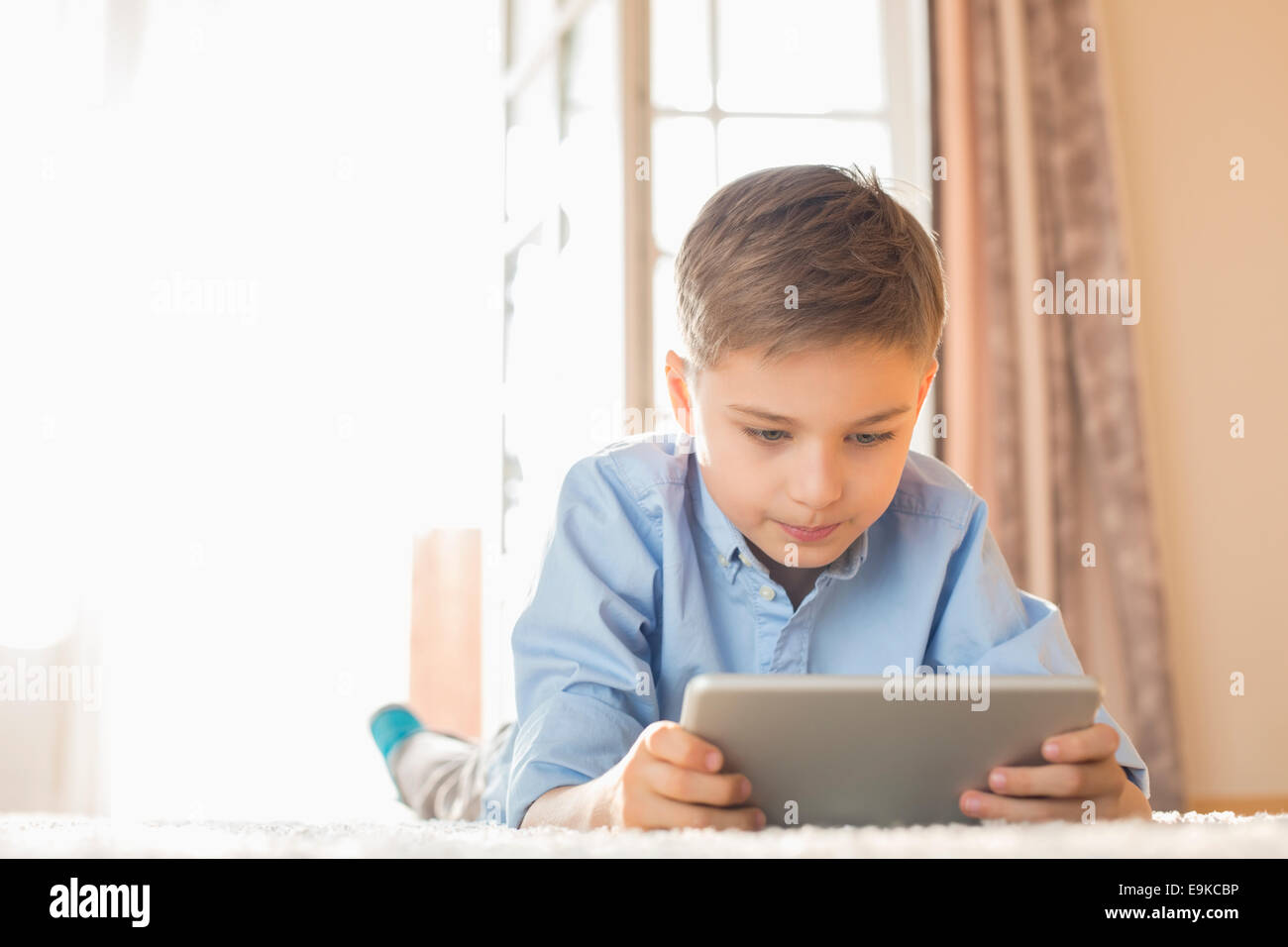 Boy using digital tablet while lying on floor at home Stock Photo - Alamy