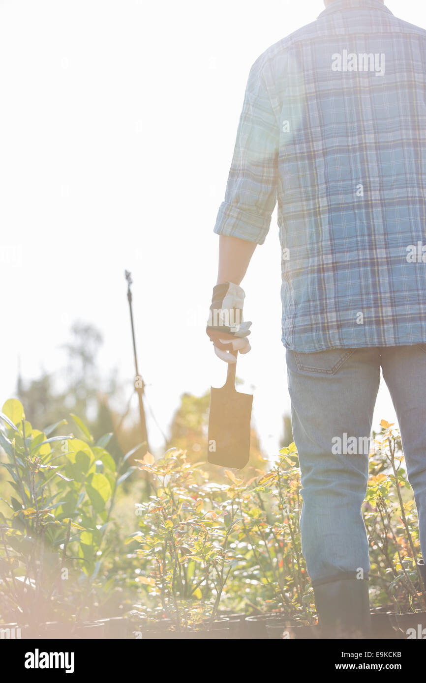 Rear view of gardener holding shovel at plant nursery Stock Photo - Alamy