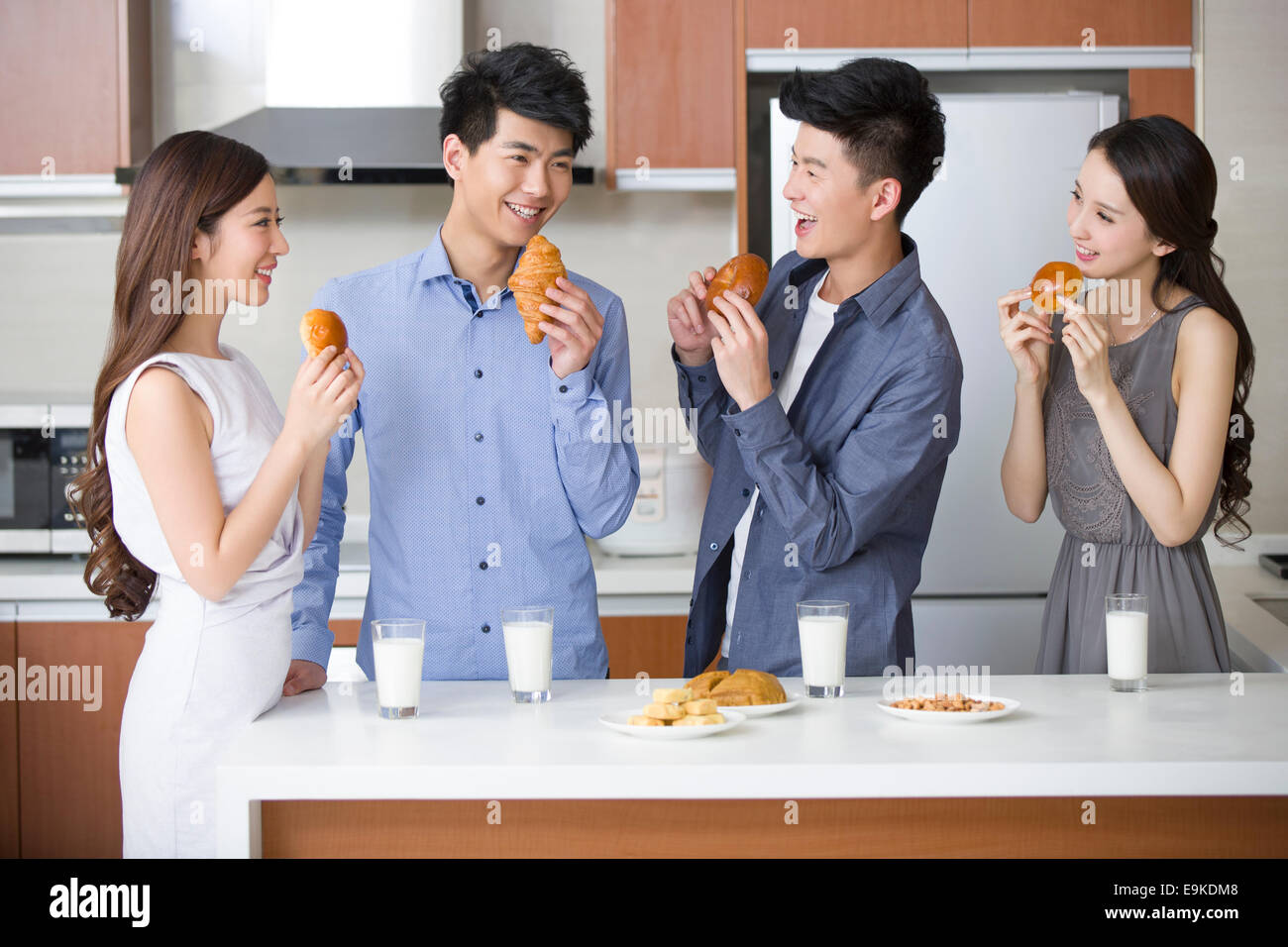 Happy young friends eating breakfast in the kitchen Stock Photo - Alamy