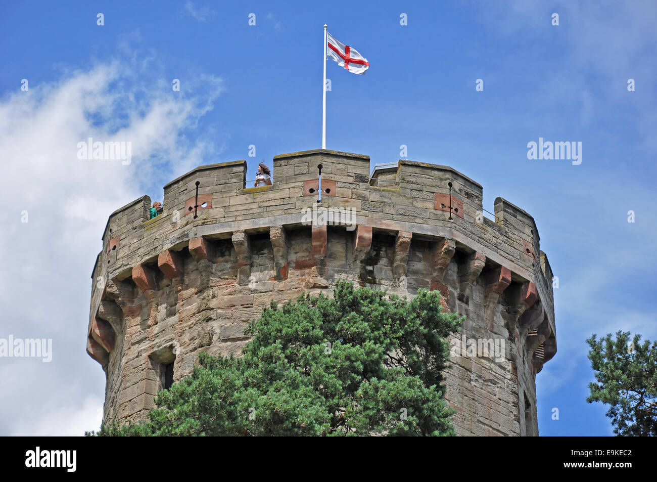 Two people looking out from a turret of Warwick castle, with a flag of ...