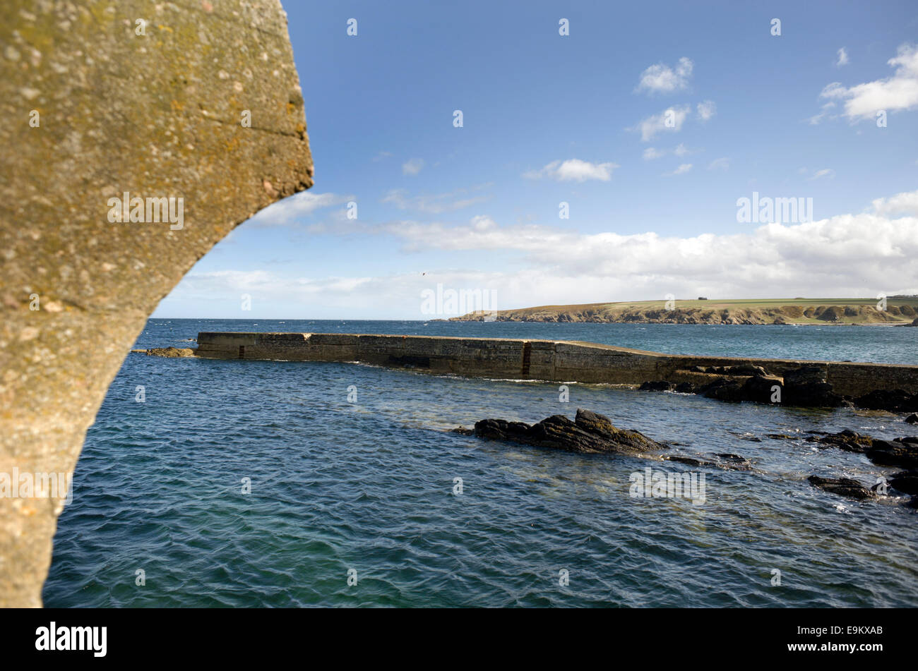 An angled section of harbour wall in the foreground as you look across ...