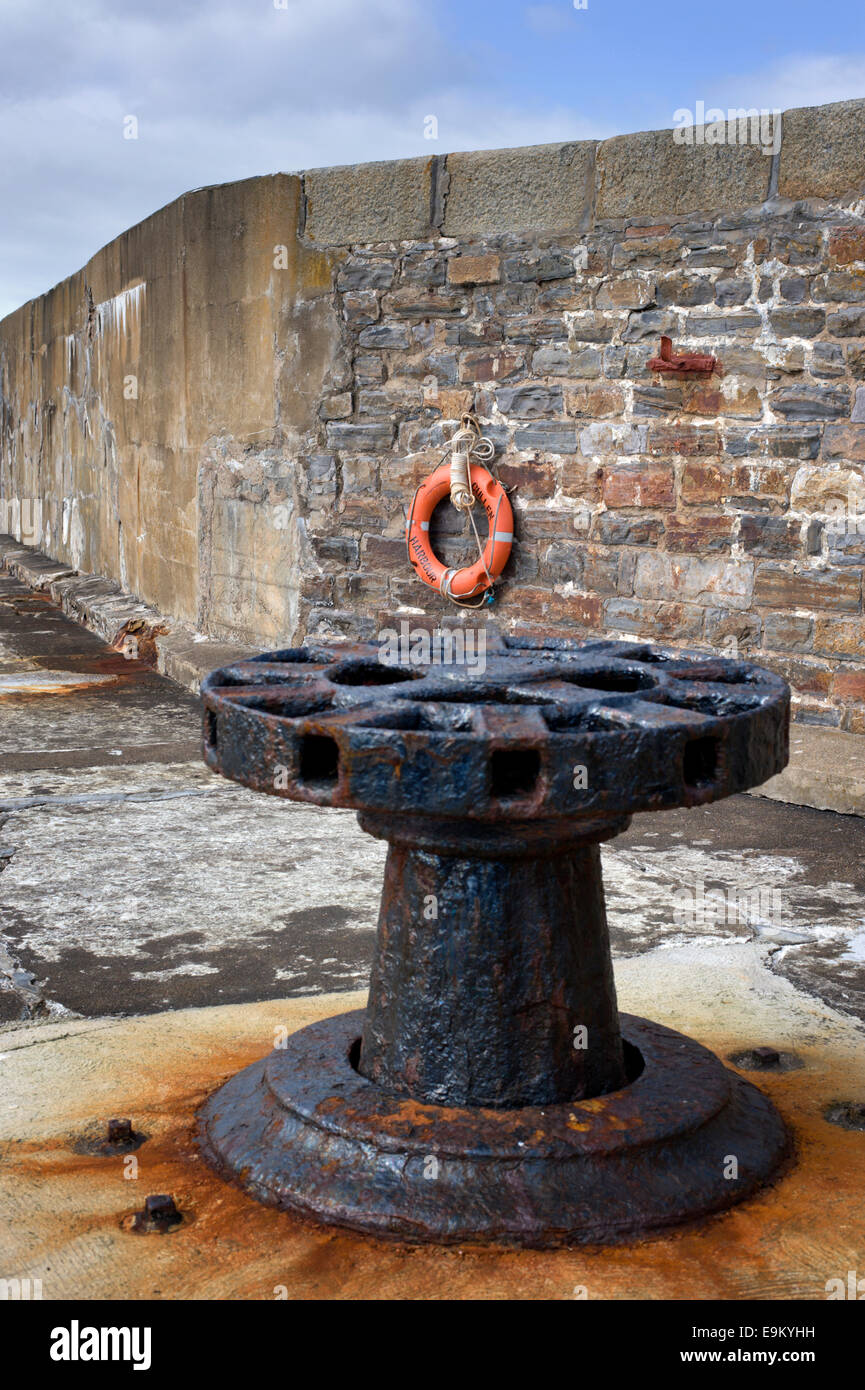 Rusty old harbourside capstan at Cullen with the main harbour wall in ...