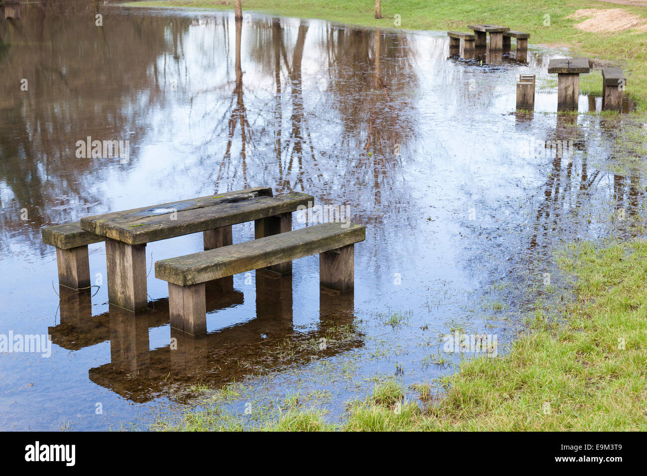 Wooden picnic benches and tables are partially submerged by flood water ...