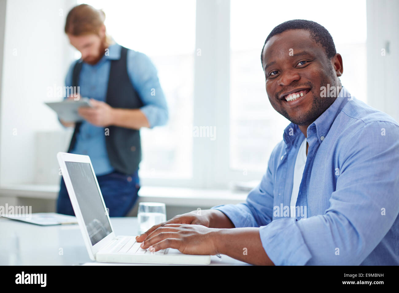 Modern African-american businessman looking at camera while networking ...