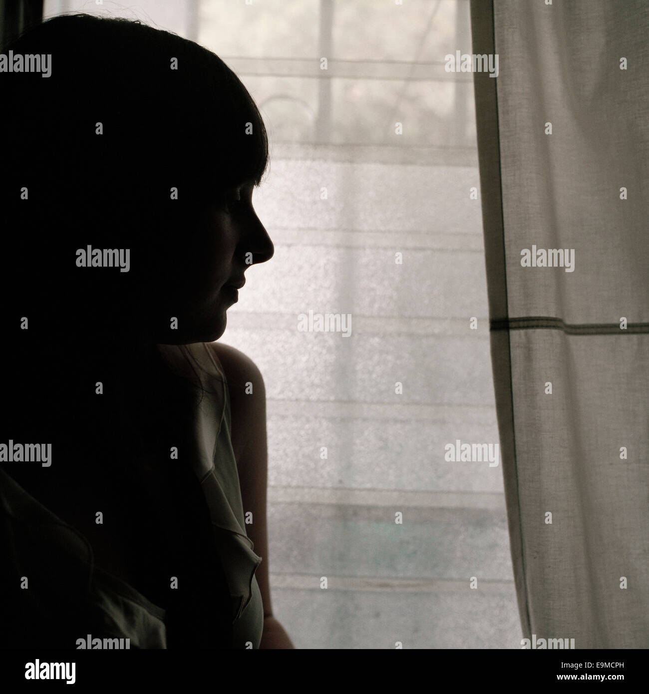 A woman standing next to a window Stock Photo - Alamy